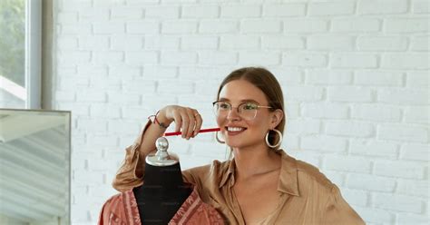 유행 아틀리에에서 일하는 디자이너 작업장에서 우아한 드레스를 만드는 아름다운 재단사 성공 자영업자는 세련된 옷을 입고 마네킹에 손을 대고 무언가를 스케치할 것입니다