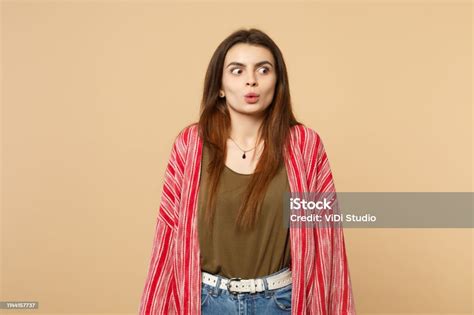 깜짝 놀란 젊은 여자의 초상화는 서 서 옆에 있는 파스텔 베이 지 벽 배경에 고립 된 스튜디오에서 사람들은 진심으로 감정 라이프 스타일 개념입니다 복사 공간을 모의 합니다