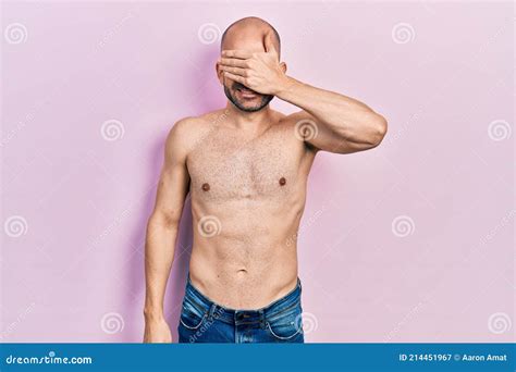 Young Bald Man Standing Shirtless Smiling And Laughing With Hand On