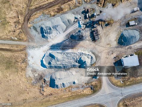 생산을 위한 작은 공장의 공중 보기와 회색 연기가 간다 파이프에서 건축 자재 더미 근처 잔해와 시멘트를 청소 트랙터 완제품을 수송 한다 건설 기계류에 대한 스톡 사진 및