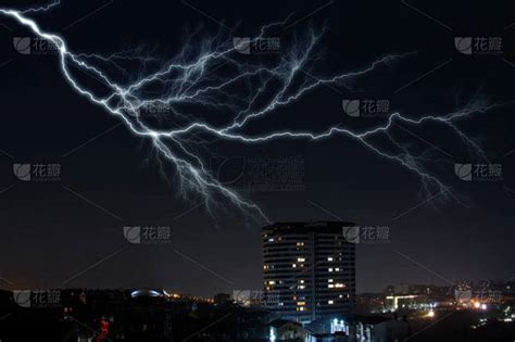 在亚美尼亚埃里温在灯光明亮的建筑物上方在漆黑的夜空中闪烁着风暴和闪电形成了戏剧性的对比场面