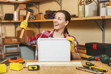 격자 무늬 셔츠에 젊은 여자 나무 테이블에서 목공 워크숍에서 노란색 장갑 망치 빈 프레임 다양 한 도구와 장소 텍스트에 대 한 빈 자리와 광고에 대 한 공간을 복사 합니다