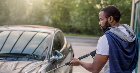 야외에서 세차 서비스 흰색 티셔츠와 청바지를 입은 아프리카 남자의 측면 모습 야외 셀프 세차장에서 물총으로 파란색 전기 고급 자동차 세척 사진 Unsplash의 세차 이미지