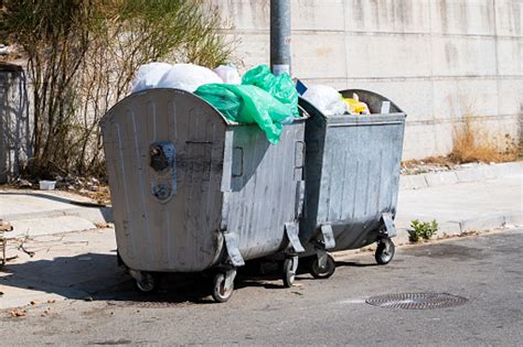 도시의 도로에있는 금속 쓰레기통은 모든 종류의 쓰레기로 가득합니다 인간 오염 폐기물과 쓰레기의 상처 및 재활용을위한 지정된 지역 산업 폐기물 수거통에 대한 스톡 사진 및