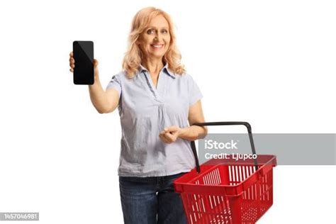 스마트폰을 보여주는 빨간 쇼핑 바구니를 가진 웃고 있는 성숙한 여자 55 59세에 대한 스톡 사진 및 기타 이미지 55 59세 고객 구매 Istock