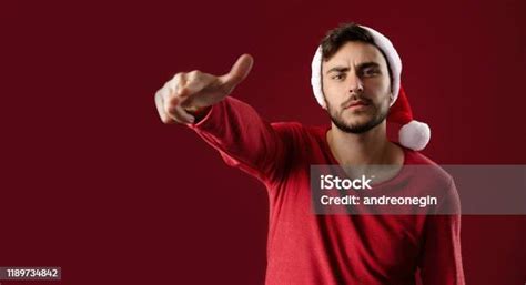 빨간 스웨터와 산타 모자를 입은 젊은 잘생긴 백인 남자가 스튜디오에서 빨간색 배경에 서서 카메라에 손가락을 보여줍니다 12월에 대한 스톡 사진 및 기타 이미지 Istock