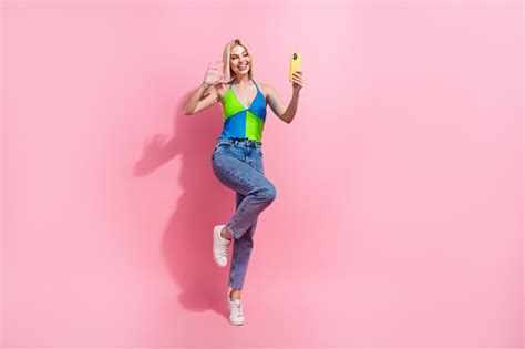 예쁜 소녀 옷을 입은 화려한 탱크 데님 바지 손을 흔들며 스마트 폰에 셀카를 만드는 전체 길이 사진 핑크 컬러 배경에 고립 된 25 29세에 대한 스톡 사진 및 기타 이미지