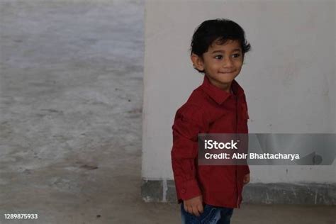 흰색 도시 배경의 발코니에 서있는 동안 활기찬 빨간 셔츠를 입고 인도 귀여운 작은 쾌활한 갈색 머리 타밀 아기 소년의 초상화 2 3 살에 대한 스톡 사진 및 기타 이미지