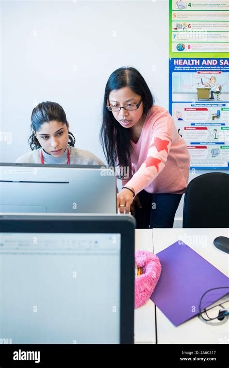 A Computer Technology Class With Students Working And Helping Each