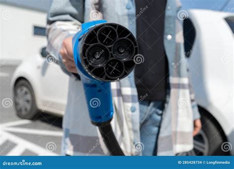 Woman Holding Fast Charging Socket CHAdeMO Plug For Electric Vehicles At EV Car Charging Station