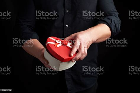 검은 셔츠를 입은 성인 남성이 활을 가진 하트 모양의 빨간 판지 상자를 들고 있습니다 검은색에 대한 스톡 사진 및 기타 이미지 검은색 긍정적인 감정 표현 기념일