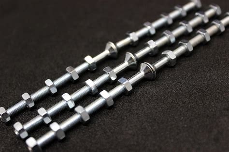 premium photo shiny iron bolts with nuts screwed on them lie in even