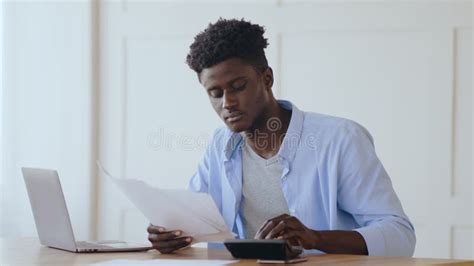 Young African Man Calculating Costs And Income At Home Office Stock
