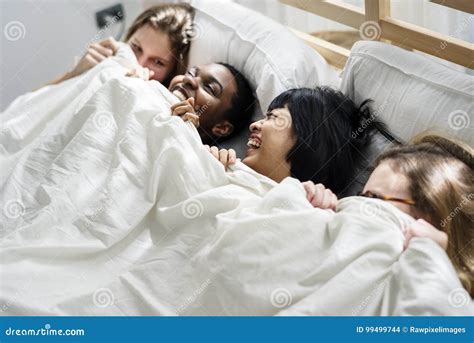 Group Of Diverse Women Lying On Bed Together Covered With Blanket Stock