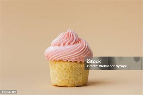 핑크 휘핑 버터 크림 탑을 곁들인 바닐라 컵케이크의 클로즈업 작은 분홍색 하트 모양의 초콜릿 토핑으로 장식 된 머핀에 크림 치즈 프로스팅 베이지색 배경입니다 해피 발렌타인