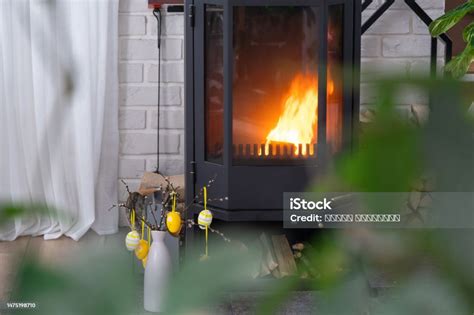 화재와 장작이 있는 벽난로 스토브 근처의 부활절 장식 화분에 심은 계획 화려한 부활절 달걀 부활절 토끼 및 꽃다발이있는 아늑한 집 난로 시골집에서 봄 겨울에 대한 스톡 사진