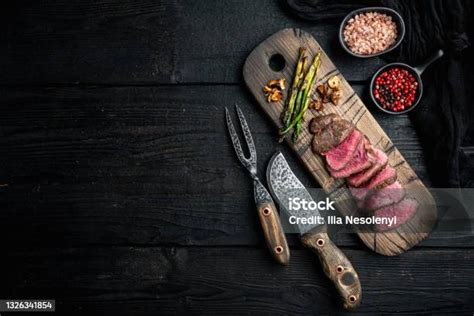 육즙 이 많은 스테이크 중간 희귀 쇠고기 Filet Mignon 또는 아이 필레 양파와 아스파라거스 나무 서빙 보드에 고기 칼과