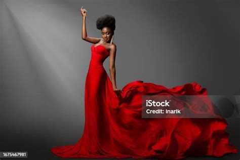 무대에서 빨간 드레스를 입고 춤을 추는 아름다운 여자 긴 가운 옆모습의 패션 어두운 피부 모델 회색 배경 위에 아프리카 머리