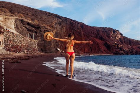 Sexy Woman In Bikini Walks On Red Beach In Santorini By Sea Girl Runs