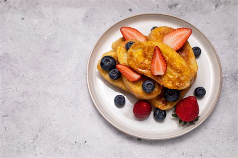 Torrijas 오렌지 토핑 유약 신선한 블루 베리 녹색 접시에 딸기 나무 테이블과 함께 제공되는 스페인 스타일의 프렌치 토스트 오렌지의 절반 스페인 디저트 평면 0명에