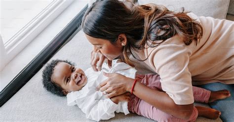 행복한 미소를 짓는 젊은 인도 어머니는 흑인 여자 딸과 놀고 있다 가족 혼혈 사람들은 엄마와 아이가 함께 집에서 껴안고