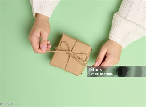 녹색 배경에 선물 상자를 들고 있는 여성의 손입니다 위에서 본 모습 갈색에 대한 스톡 사진 및 기타 이미지 갈색 공휴일 기념일 Istock