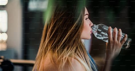 어린 소녀 또는 여자가 체육관에 서서 병에서 물을 마시는 측면보기 사진 Unsplash의 운동 이미지