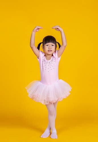 노란 배경에 고립 된 분홍색 투투 스커트에 발레리나가되는 작은 아시아 어린이 소녀의 초상화 행복한 어린 소녀는 그녀의 춤을 연습합니다 교육 어린 시절 유아 라이프 스타일