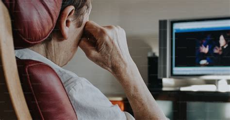 집에서 팔걸이 의자에 앉아 Tv를 보고 있는 늙은 여자 잠겨 있는 성숙한 노인 여성은 텔레비전에서 뉴스를 듣고 있다 오래 된 불행한 인간 여자의 감정적 인 초상화