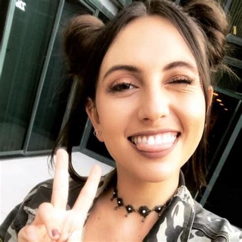 A Woman Is Making The Peace Sign With Her Hand And Smiling At The Camera While Standing In Front