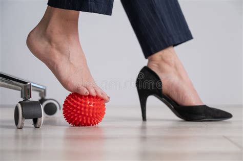 Business Woman Massages Her Feet On A Massage Ball With Spikes Stock