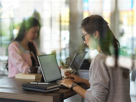 유리창을 통해 카페에서 노트북으로 작업하는 두 여성의 모습 사진 Unsplash의 기술 이미지