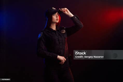 심각한 여성 경찰관은 빨간색과 파란색 백라이트와 검은 배경에 대한 카메라를 위해 포즈를 취하고있다 검은색에 대한 스톡 사진 및 기타 이미지 Istock
