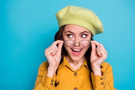 깜짝 놀란 긍정적 인 쾌활한 소녀 룩 카피 스페이스 터치 사양 감동 시즌 특가 정보 착용 옐로우 셔츠 모자 블루 컬러 배경의 클로즈업 사진 안경에 대한 스톡 사진 및 기타