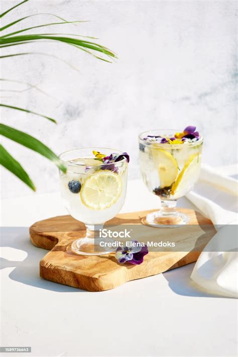 신선한 감귤류를 곁들인 차가운 칵테일과 나무 서빙 보드에 식용 꽃으로 장식되어 있습니다 소다와 과일을 곁들인 여름 음료 감귤류 과일에 대한 스톡 사진 및 기타 이미지