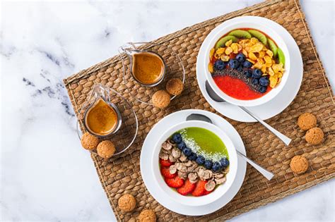 2 신선한 슬라이스 과일 밀 밀기 울 콘플레이크와 코코넛 칩 Chia의 종자 및 열매 건강 한 아침 식사는 시리얼과 딸기와 키 위에서 다른 스무디와 그릇 슈퍼 푸드와 커피