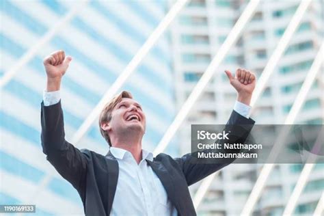 성공을 축하합니다 흥분 쾌활한 젊은 사업가 팔을 들고 백사실 건물에 야외서 있는 동안 양성을 표현 건물 외관에 대한 스톡 사진 및 기타 이미지 Istock