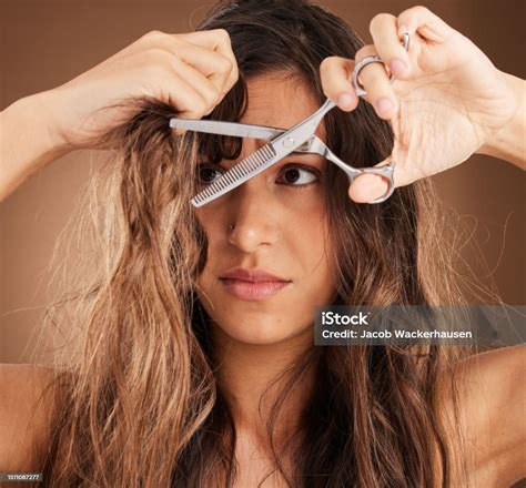 헤어 케어 손상 가위를 든 여성 걱정 살롱 컷 트리트먼트는 갈색 배경에 있다 뷰티 위기 이발 및 갈라진 끝 스튜디오 배경에서 손상된 헤어스타일을 가진 좌절한 라틴계 모델