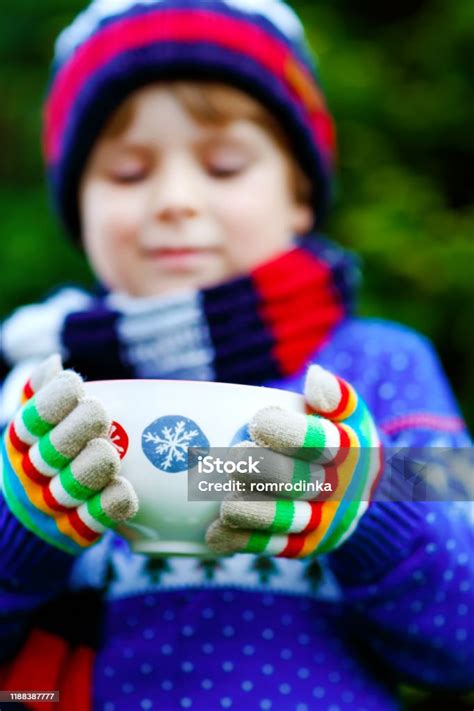 뜨거운 코코아와 초콜릿 음료와 마시멜로를 마시는 행복한 작은 아이 소년 겨울 스웨터 모자 긴 따뜻한 스카프와 화려한 장갑에 재미 아이 추운 겨울날 야외에서 눈이 내리는 날