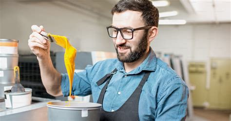 인쇄 제조소에 서 있는 오프셋 기계를 위해 노란색 페인트를 휘젓는 타이포그래퍼 사진 Unsplash의 전문 직업 이미지