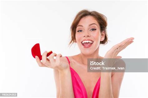 물결 모양의 갈색 패치 머리 깨끗한 피부 평평한 치아 아름다운 미소 분홍색 저지에 있는 젊은 아름다운 소녀는 훈련 반지를위한 상자를 들고 기뻐합니다 로맨스에 대한 스톡 사진