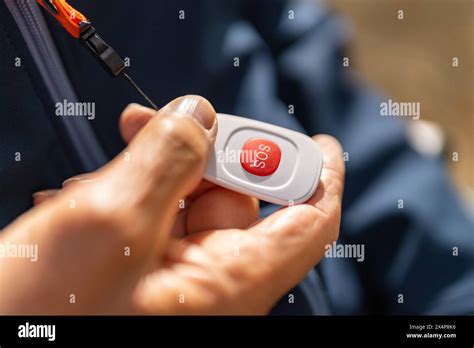 Hand Activating A Red Sos Emergency Button On A Safety Device Attached