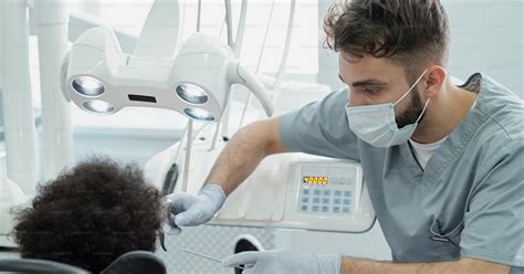 유니폼 마스크 장갑을 낀 치과의사가 작은 환자의 입으로 치과용 드릴과 기구를 들고 몸을 구부리고 있다 사진 Unsplash의 남성 치과 의사 이미지