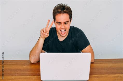 Babe Flabby Redhead Nerd Sticking Out Tongue Posing Victory Symbol To His Laptop Screen In