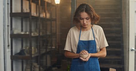 앞치마를 두른 젊은 여성 도예가가 작업장에서 조각을 준비하면서 점토를 뭉치고 있다 사진 Unsplash의 사람 이미지
