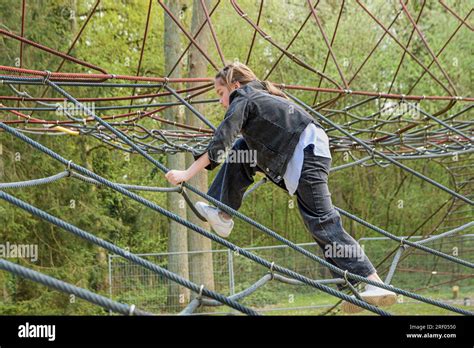 A Teenage Girl Climbs A Cobweb Attraction In A Public Park With Diligence Stock Photo Alamy