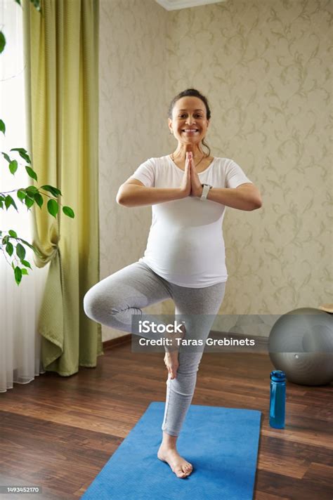 전체 길이 의식이 있는 임산부가 임신 요가를 연습하고 나마스테 손 제스처로 나무 자세로 서 있다 건강한 생활방식에 대한 스톡