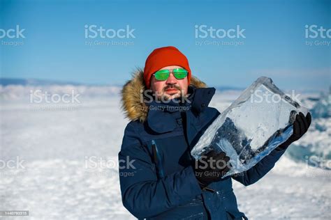 겨울 파란색 재킷과 빨간 모자를 쓰고 투명한 으깬 얼음 조각을 들고 있는 행복한 웃는 남자 겨울에 대한 스톡 사진 및 기타 이미지 겨울 겨울 코트 결정체 Istock