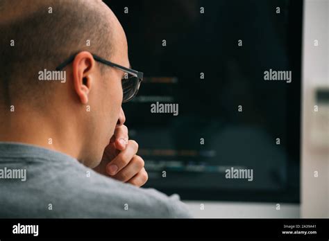 Programmer Working Behind The Desk Analysing Code On The Black Screen
