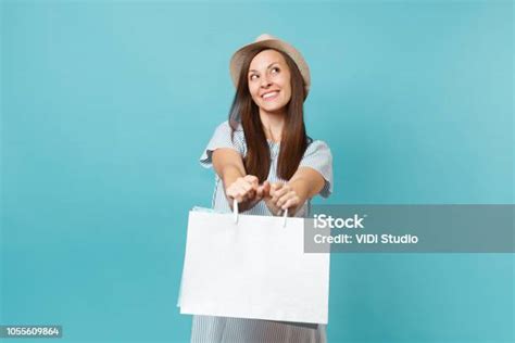 세로 행복 여름 패키지 가방을 들고 드레스 밀 짚 모자 구매 후 블루 파스텔 배경에 고립 쇼핑에 웃는 아름 다운 백인 여자 흥분 광고에 대 한 공간을 복사 가방에 대한 스톡